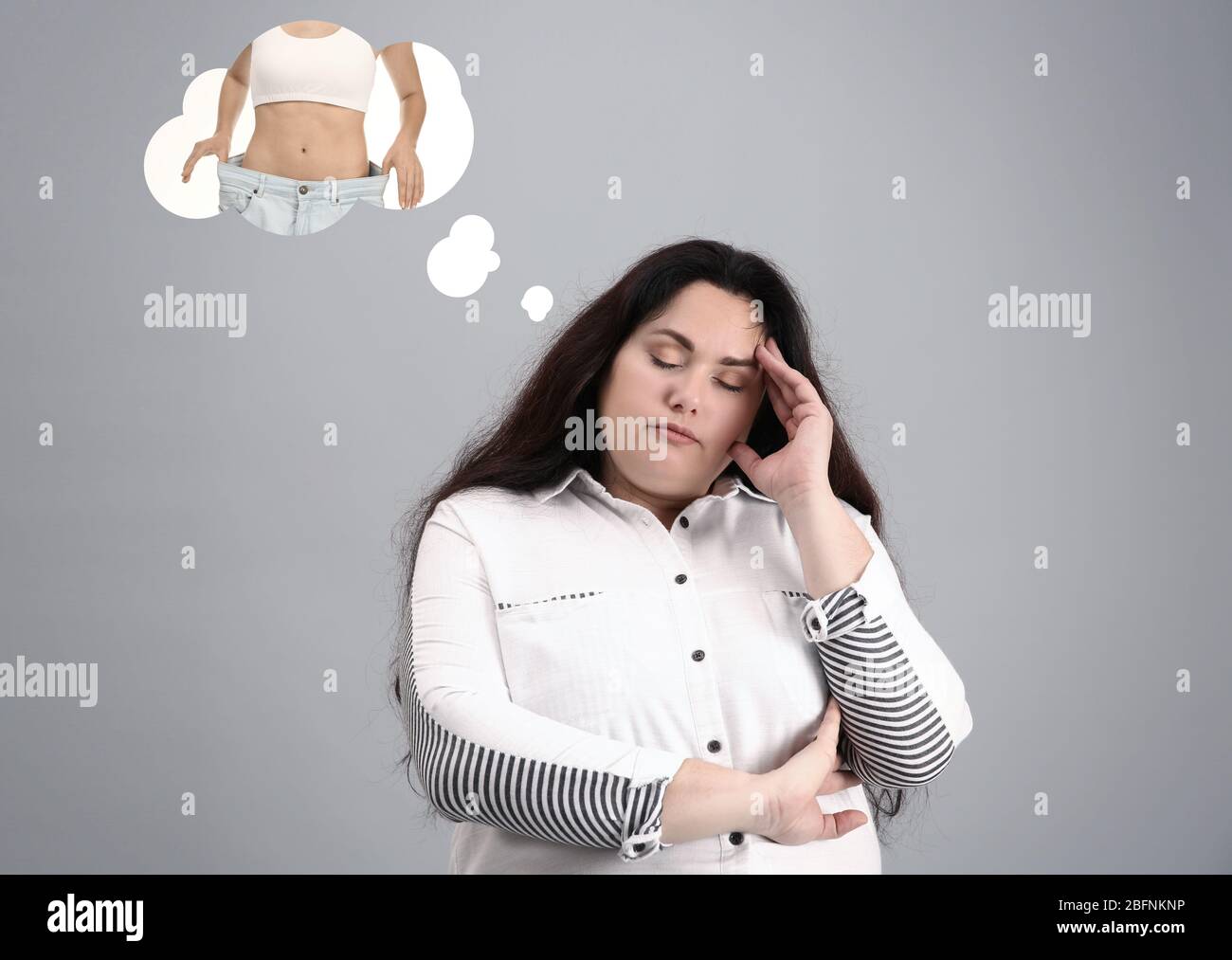 Overweight woman dreaming about slim body on grey background. Weight ...