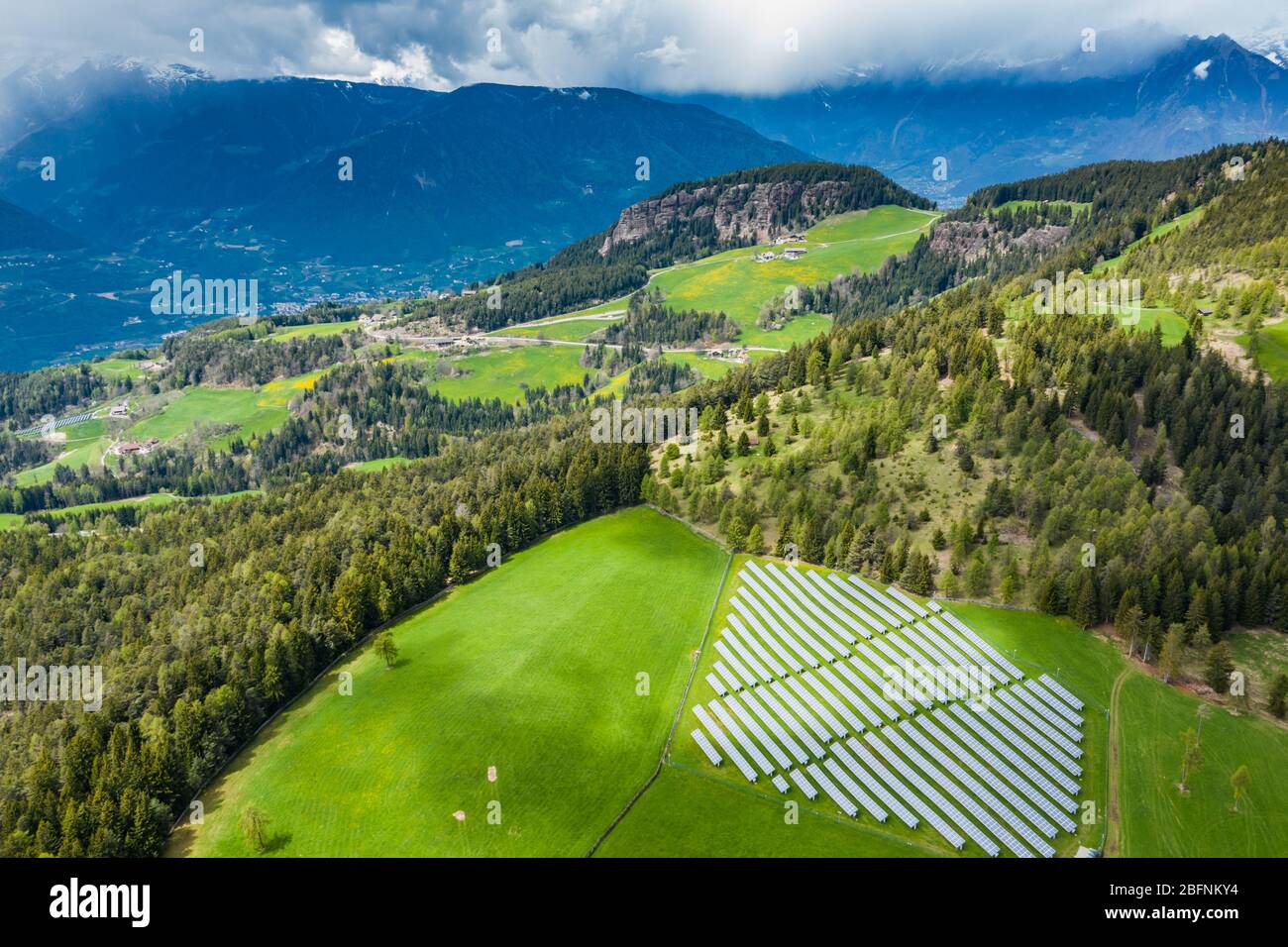 Aerial view of farm of solar batteries on green slopes of the mountains ...