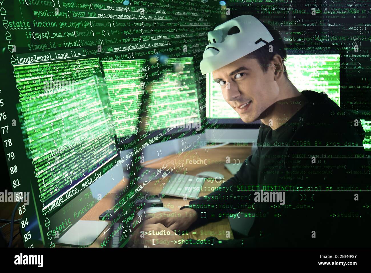 Hacker with mask using computer in darkness. Concept of cyber attack ...