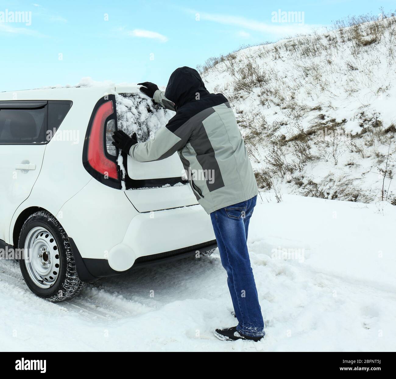 Man pushing car stuck in snowdrift on winter road Stock Photo - Alamy