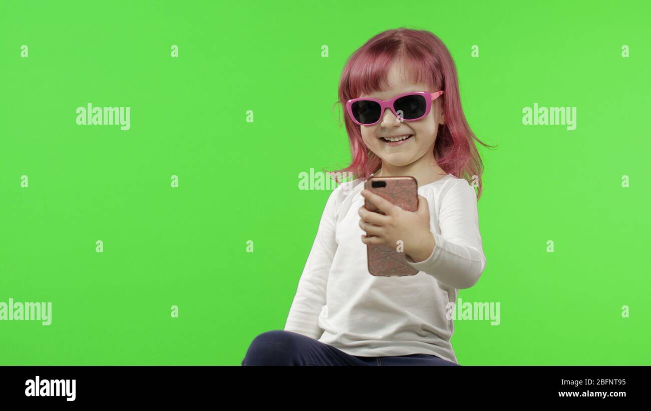 Little kid girl using smartphone. Portrait of child with pink hair in ...