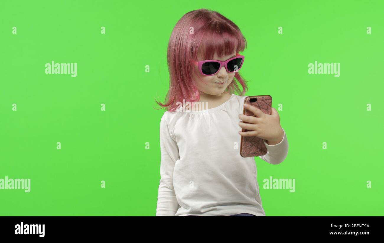 Little kid girl using smartphone. Portrait of child with pink hair in ...