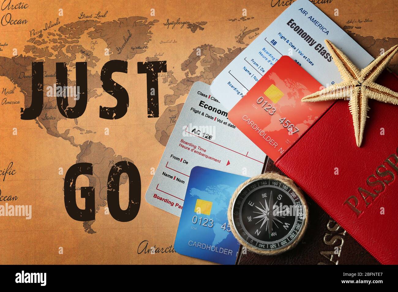 Text JUST GO, credit cards with passports and tickets on map background ...
