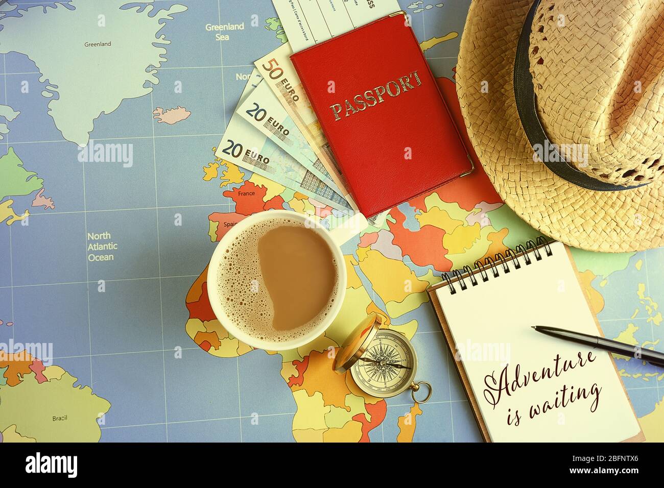 Text ADVENTURE IS WAITING written in notebook and travel stuff on world ...