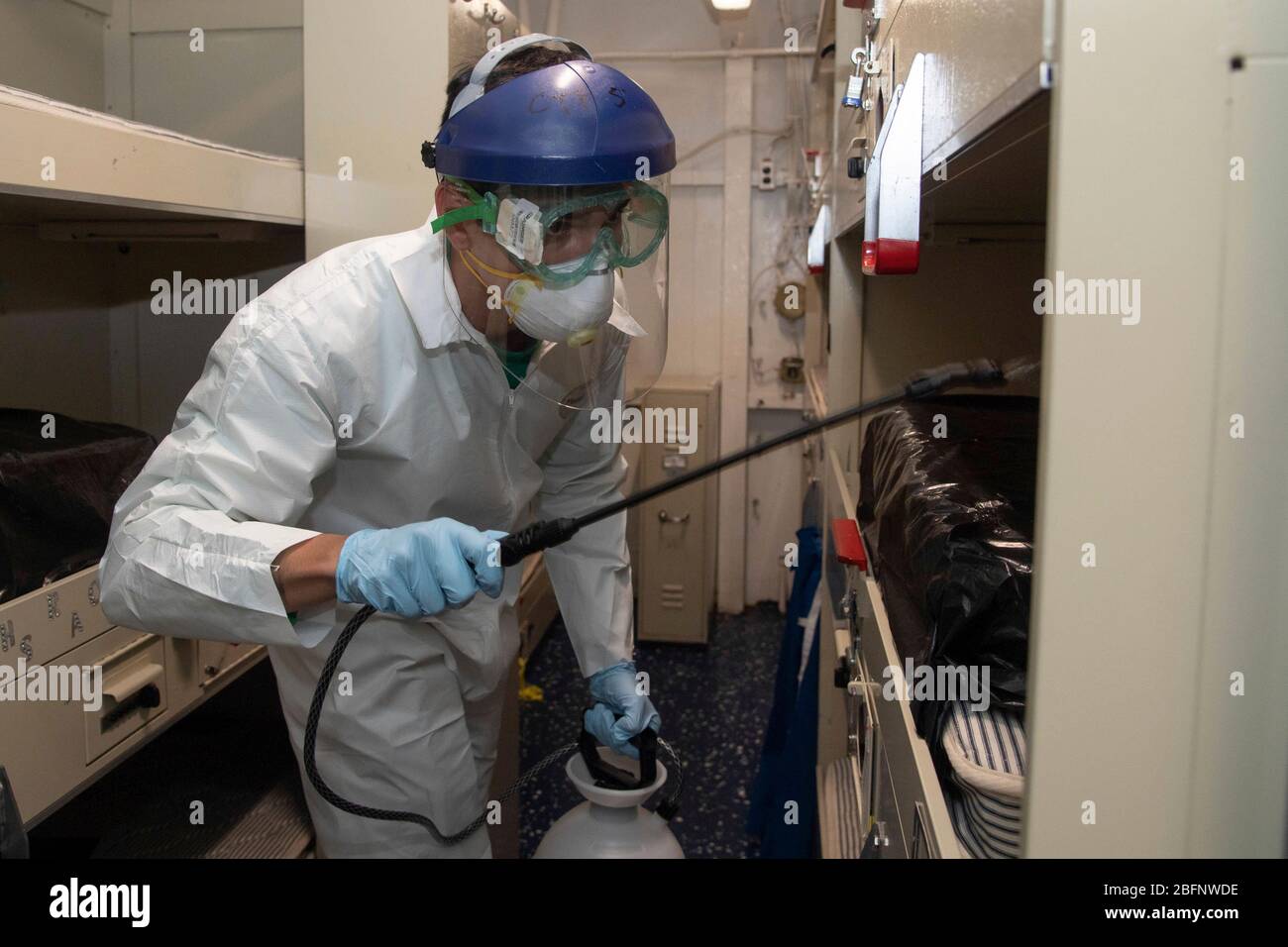 A U.S. Navy sailor disinfects a bunks aboard the aircraft carrier USS ...