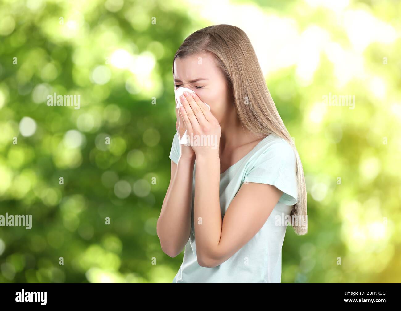 Seasonal allergy. Young woman with tissue on blurred background Stock ...