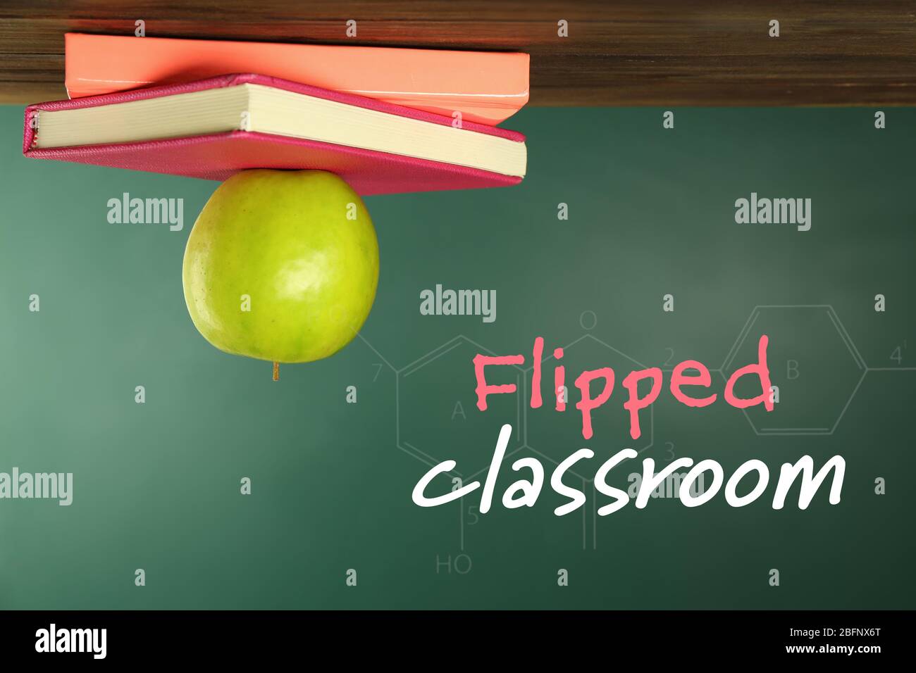 Flipped classroom concept. Inversed books and apple on blackboard ...