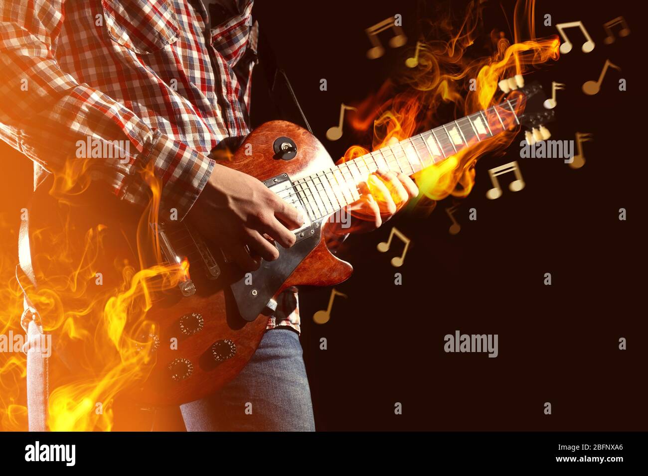 Young man playing electric guitar and fire surrounding instrument on ...