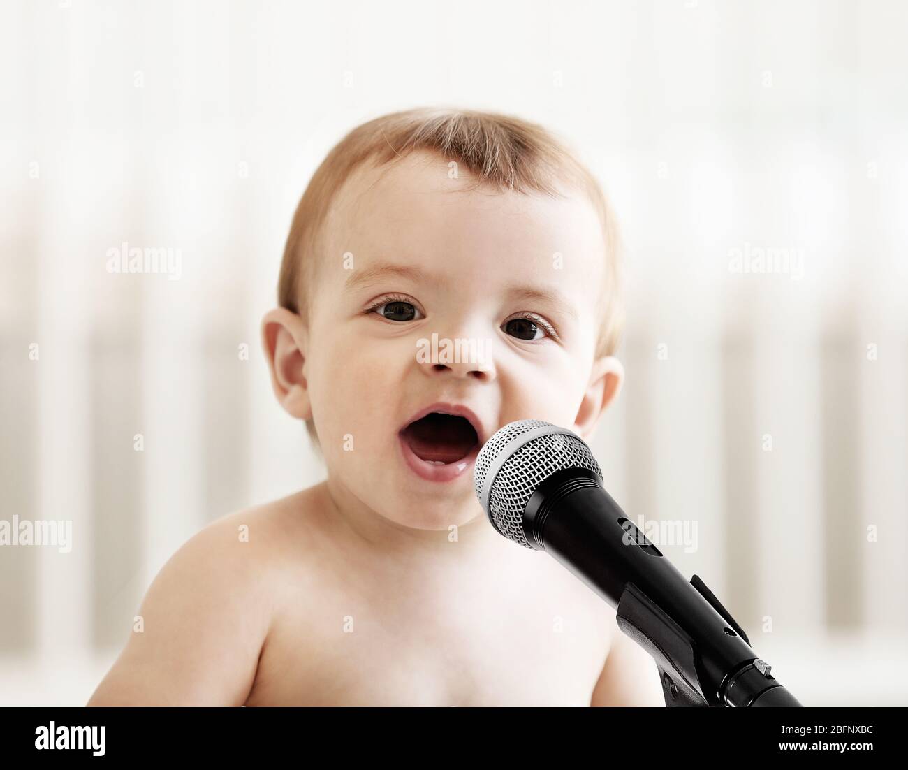 Cute baby with microphone on light background Stock Photo - Alamy