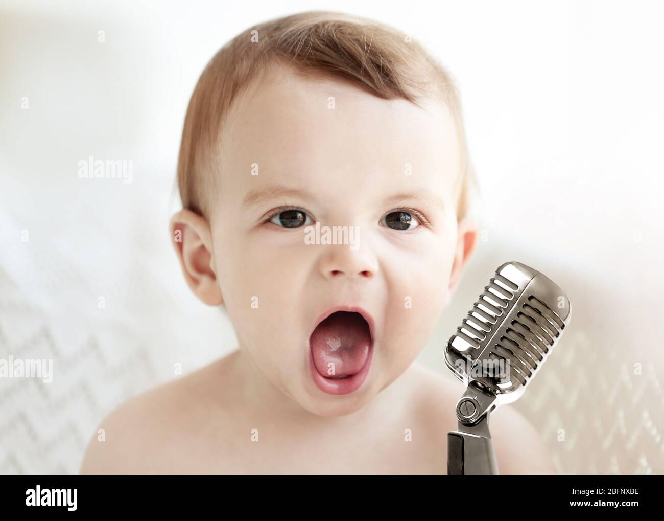 Cute baby with microphone on light background Stock Photo - Alamy