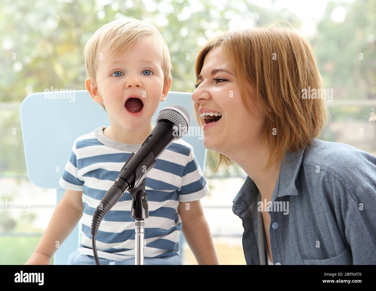 Cute baby with mother and microphone at home Stock Photo - Alamy