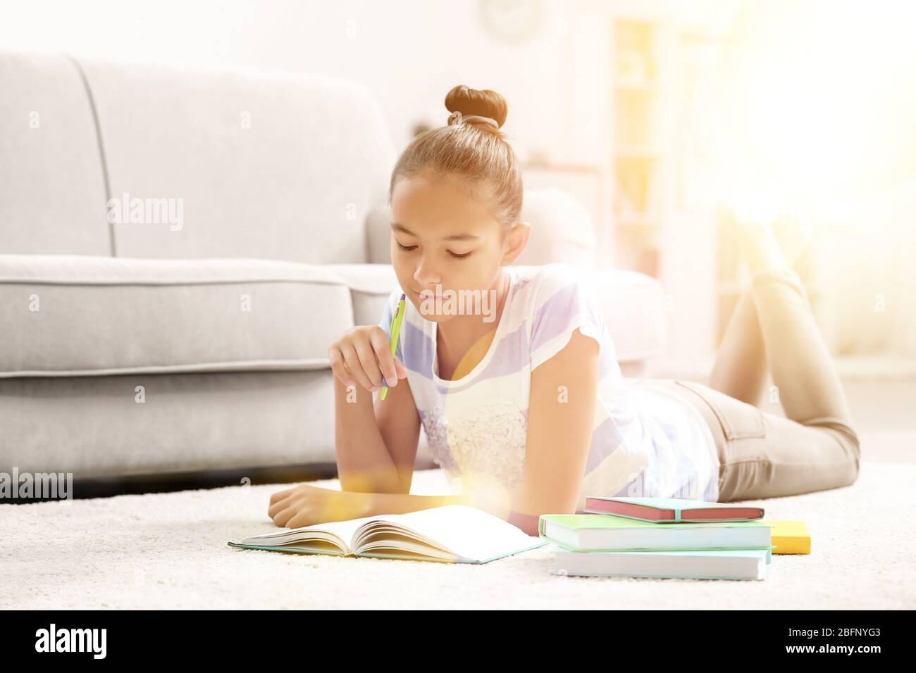 Girl doing homework on floor in room Stock Photo - Alamy