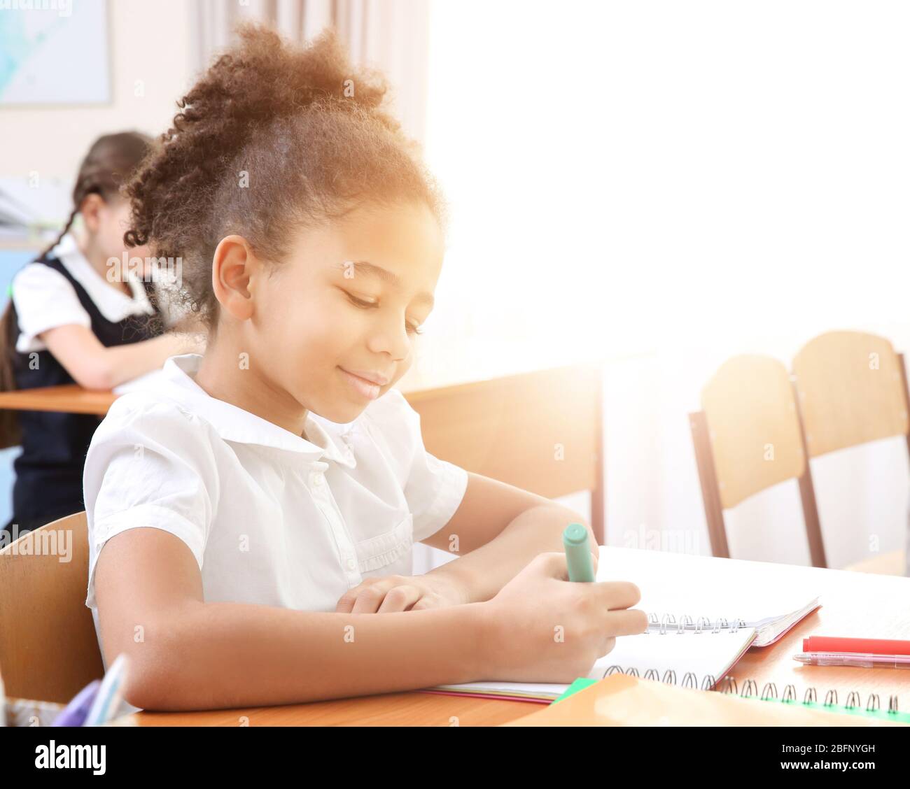 Little African-American girl doing homework at table in classroom Stock ...