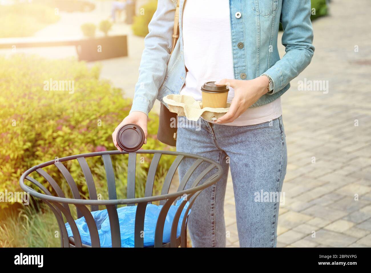 Woman throwing paper cup in litter bin outdoors. Recycling concept ...