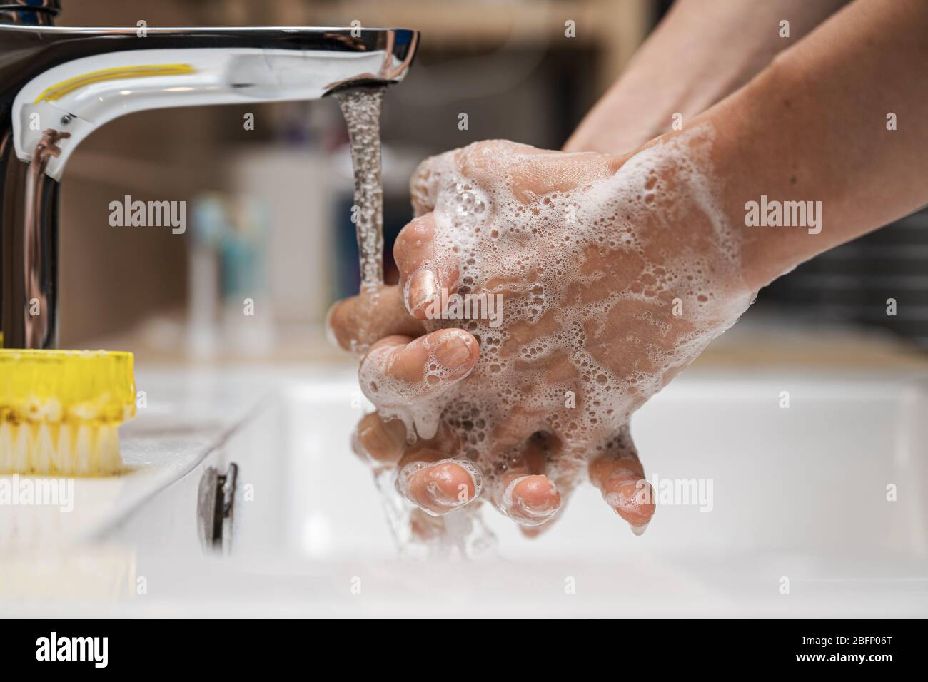 Closeup view of a woman washing her hands under clean tap water using ...