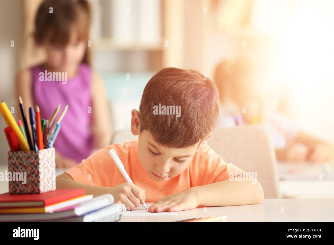 Little boy doing homework at table in classroom Stock Photo - Alamy