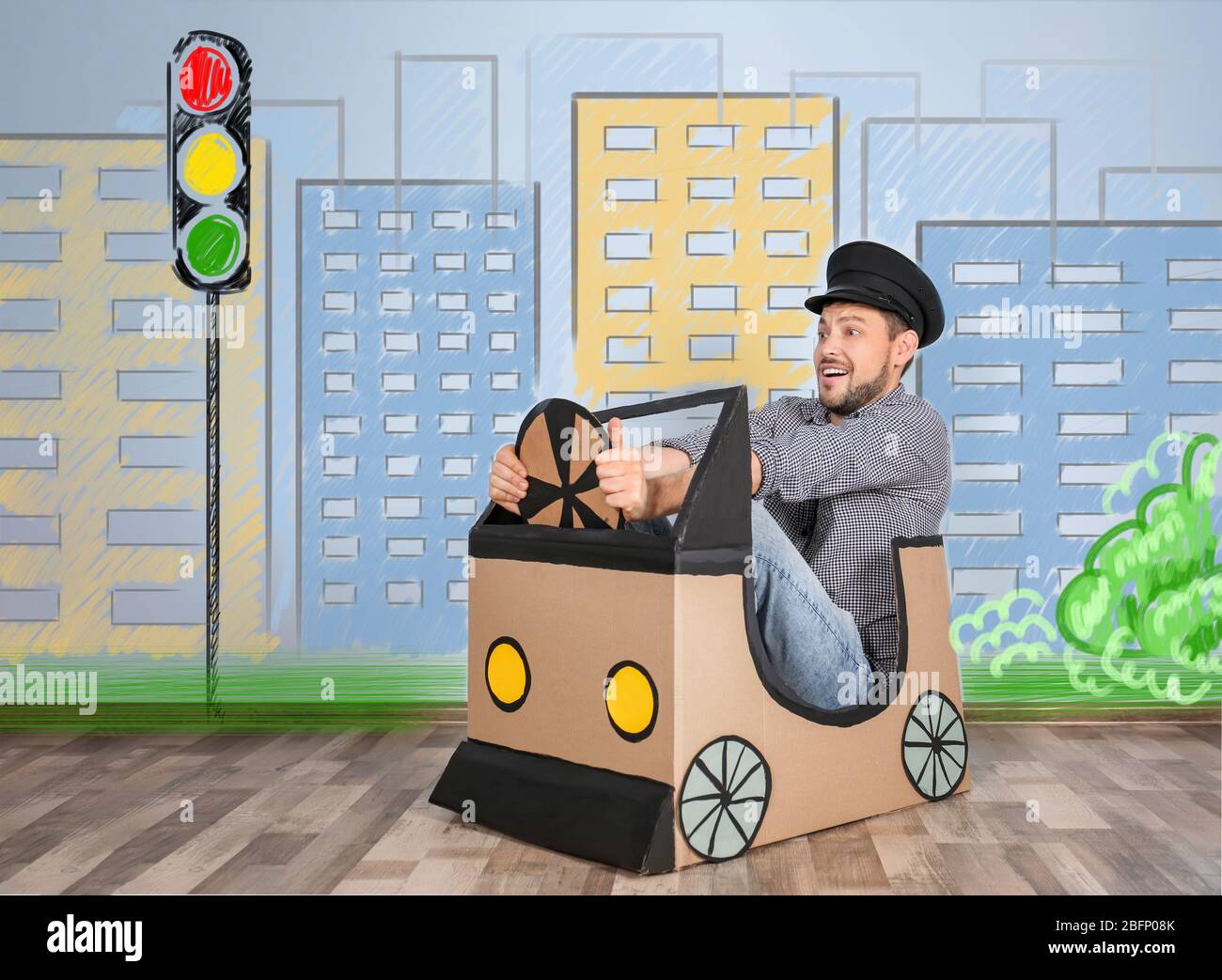 Man in cardboard auto and drawn city on background. Dreaming of car ...