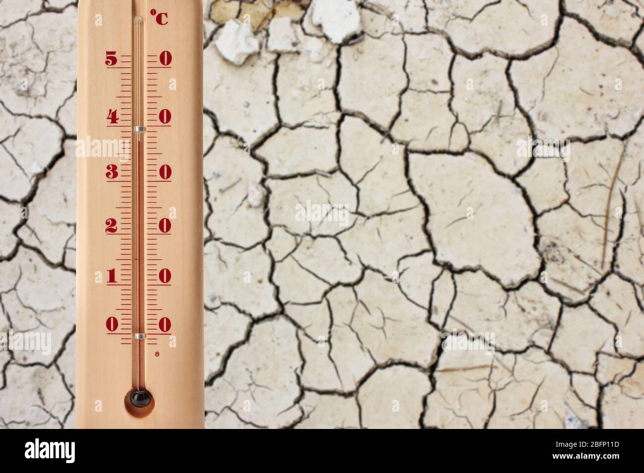 Thermometer showing high temperature and dry soil on background ...