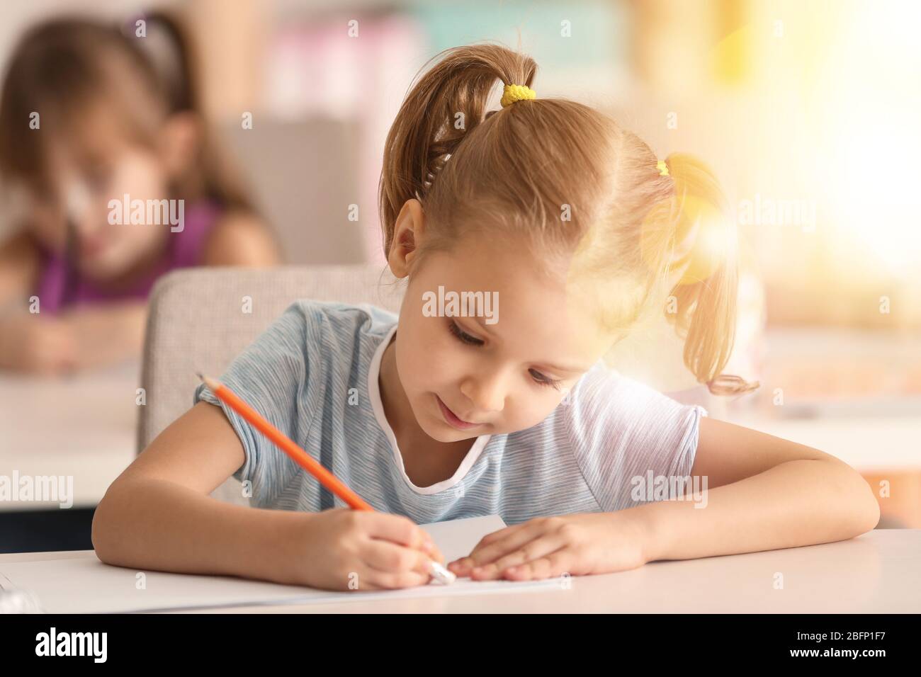 Little girl doing homework at table in classroom Stock Photo - Alamy
