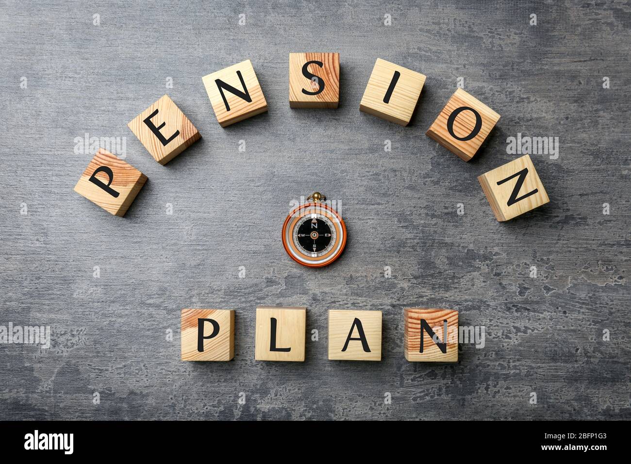 Wooden cubes with text PENSION PLAN and compass on grey background ...