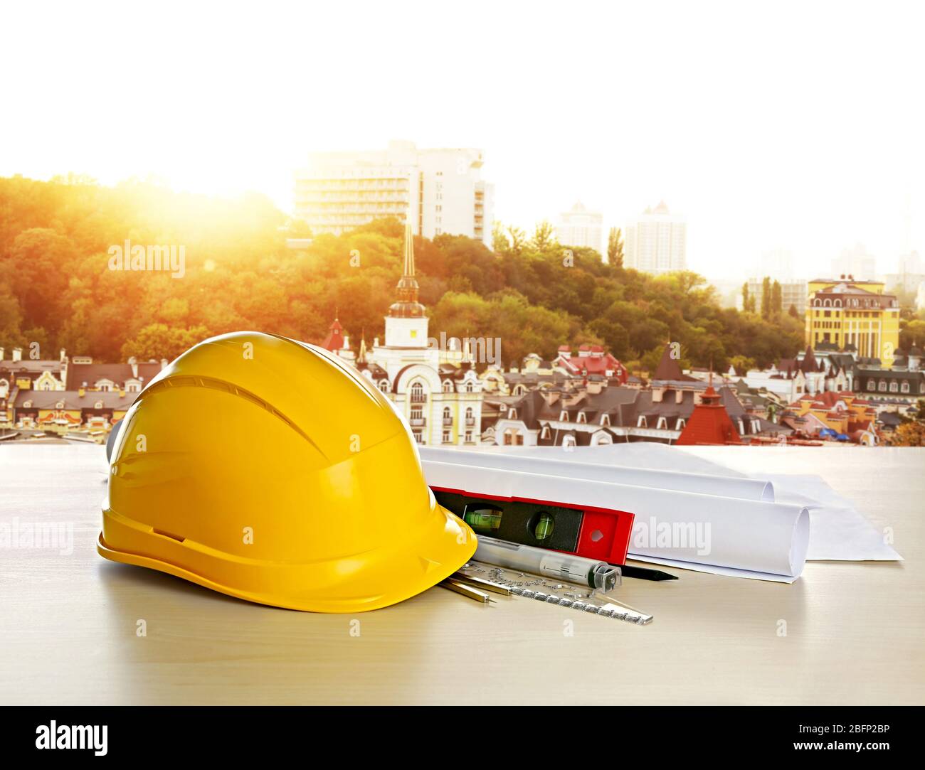 Table with construction drawings and other tools on cityscape ...
