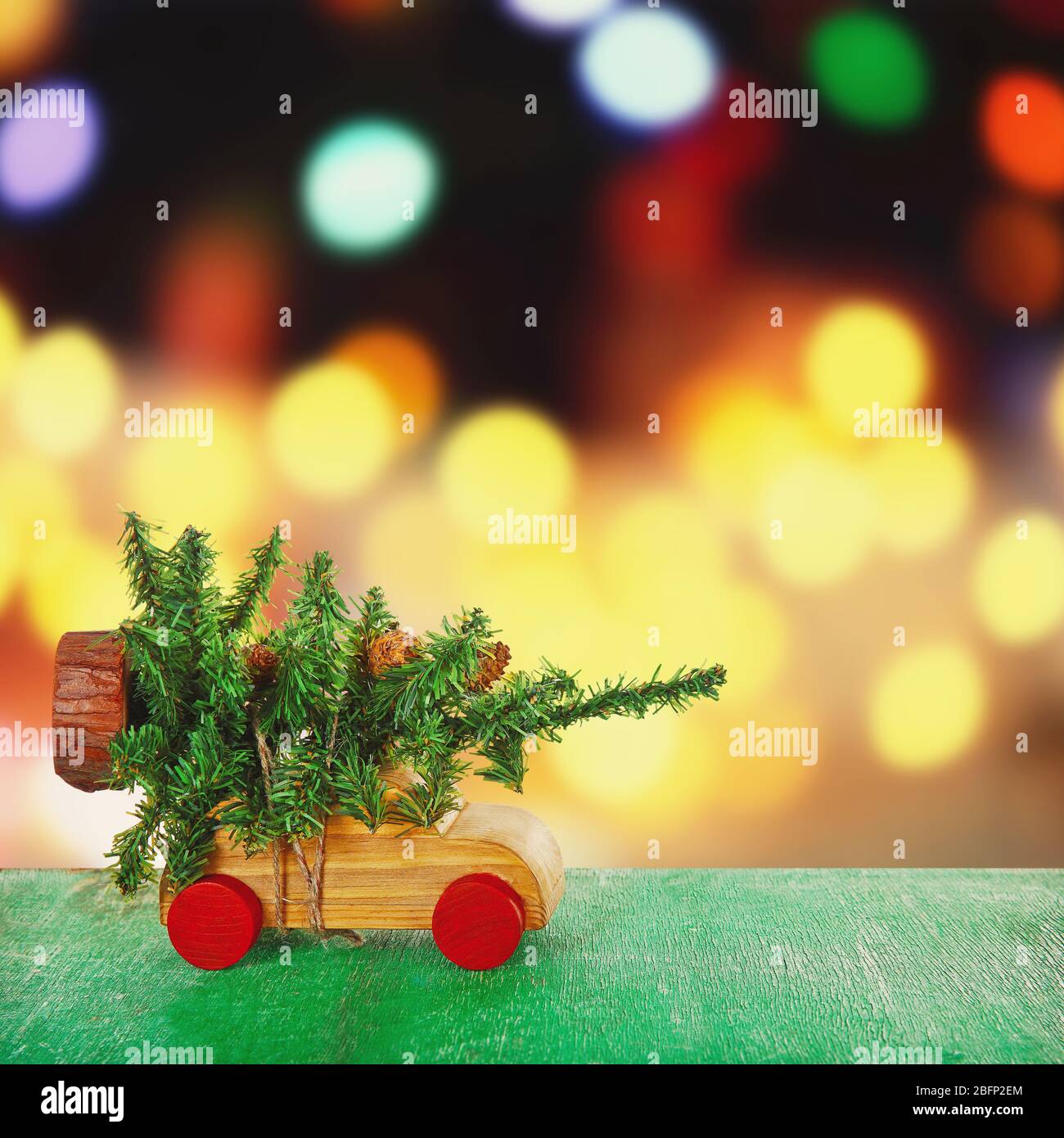 Wooden toy car carrying Christmas miniature tree on shiny lights ...