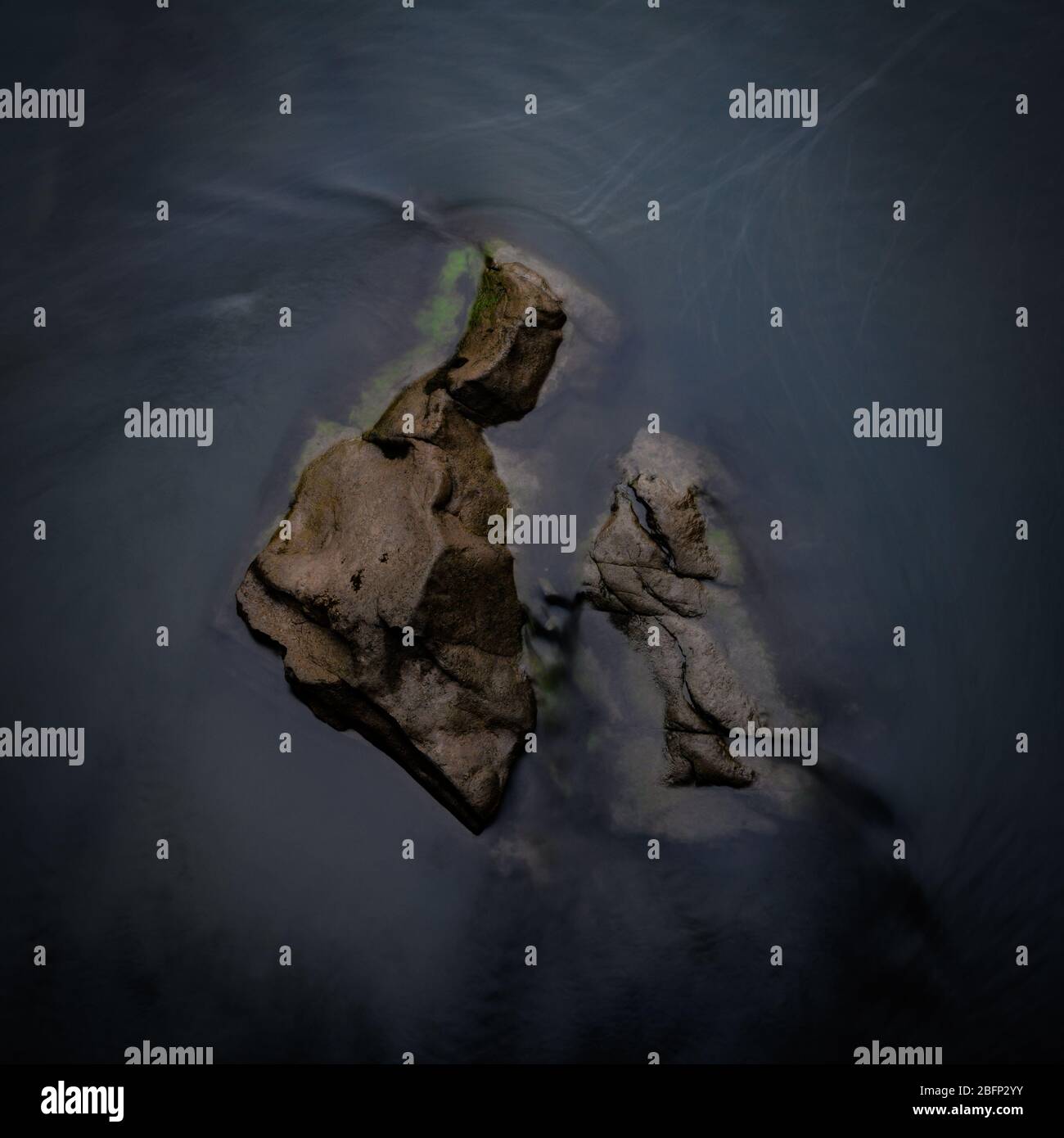 Water Rushes Around Boulders in Dark River Stock Photo - Alamy
