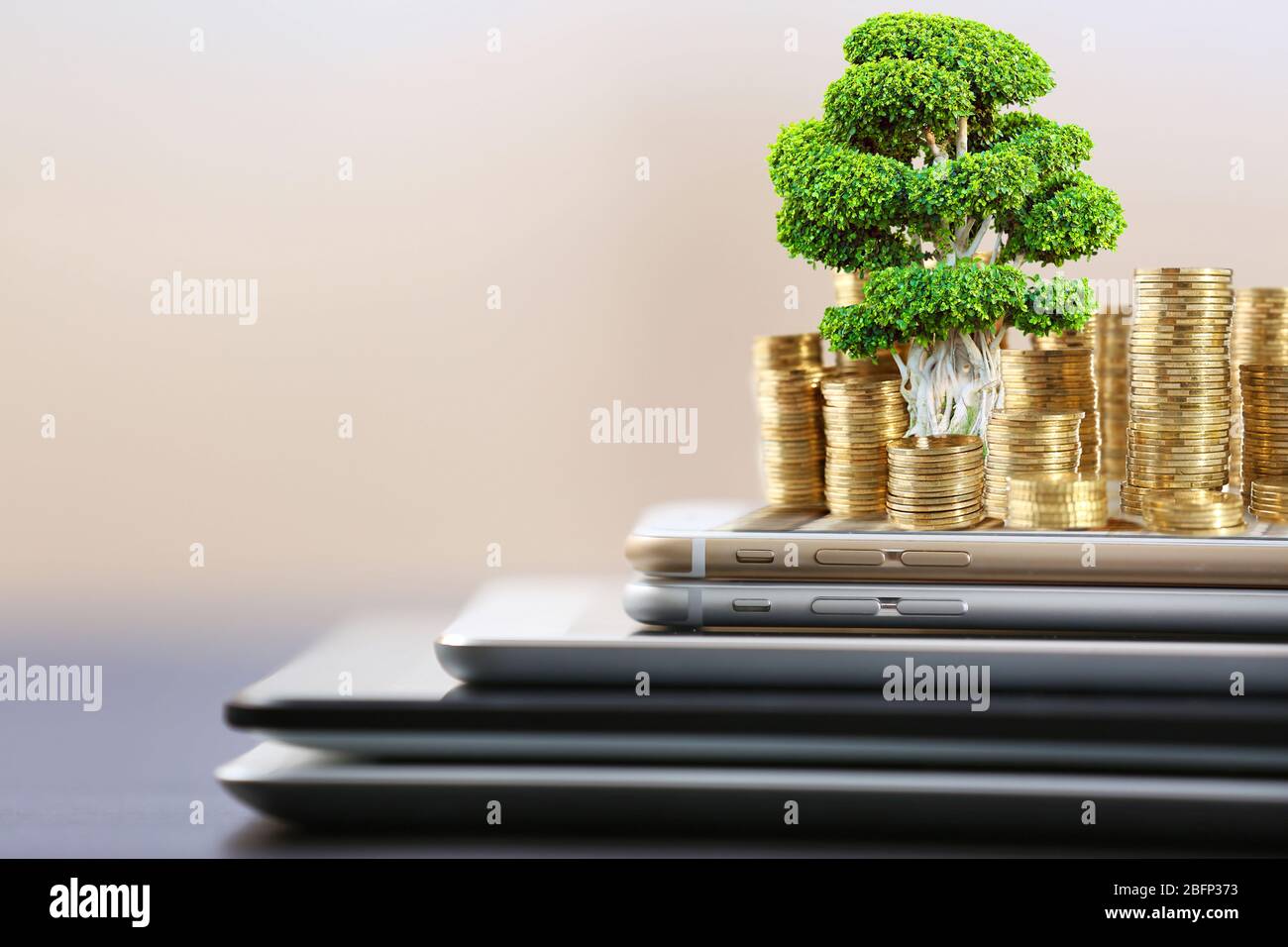 Stack of electronic devices and green tree with coins Stock Photo - Alamy