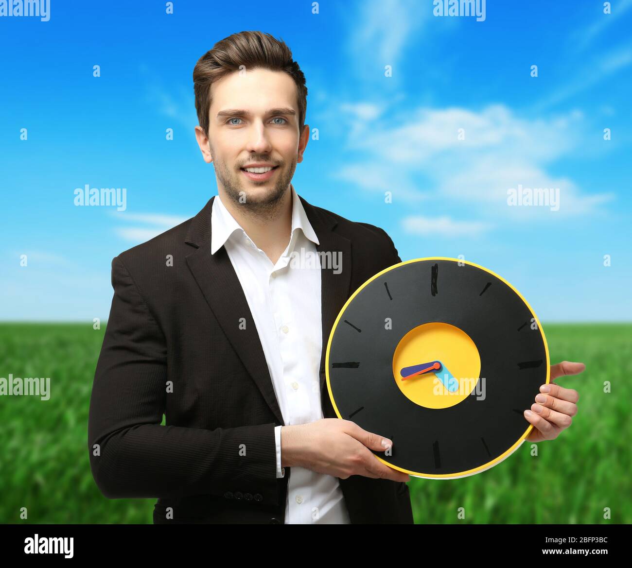 Man in black suit holding big clock on natural background Stock Photo ...