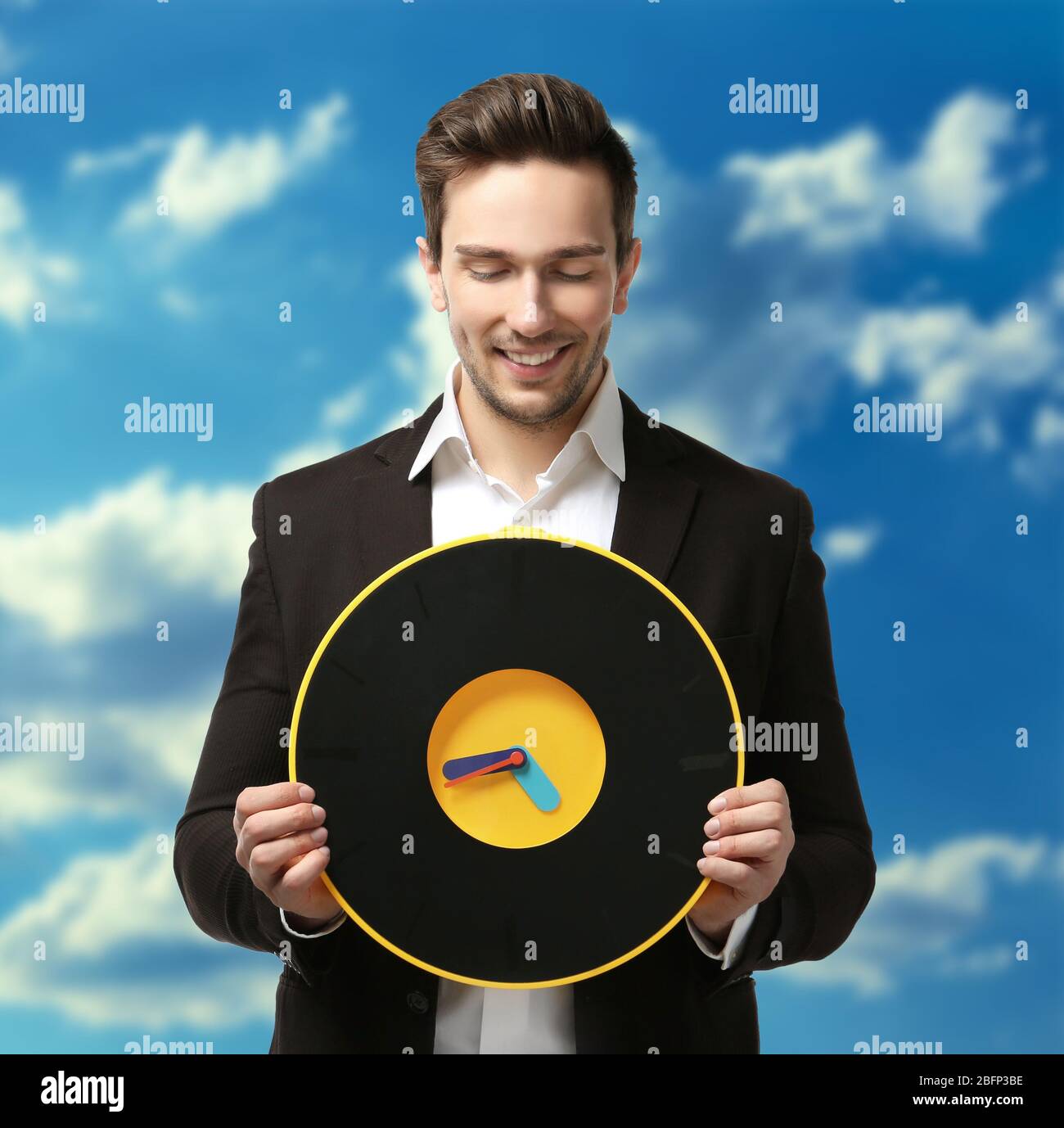 Man in black suit holding big clock on sky background Stock Photo - Alamy
