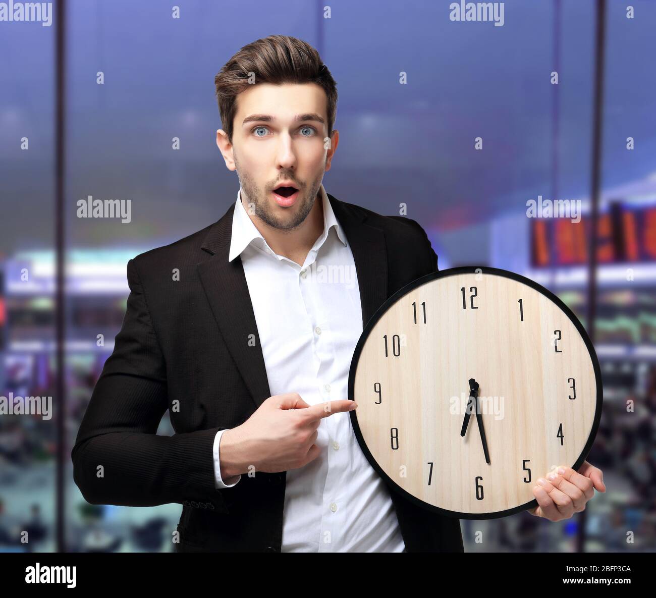 Man in black suit holding big clock on blurred urban background Stock ...