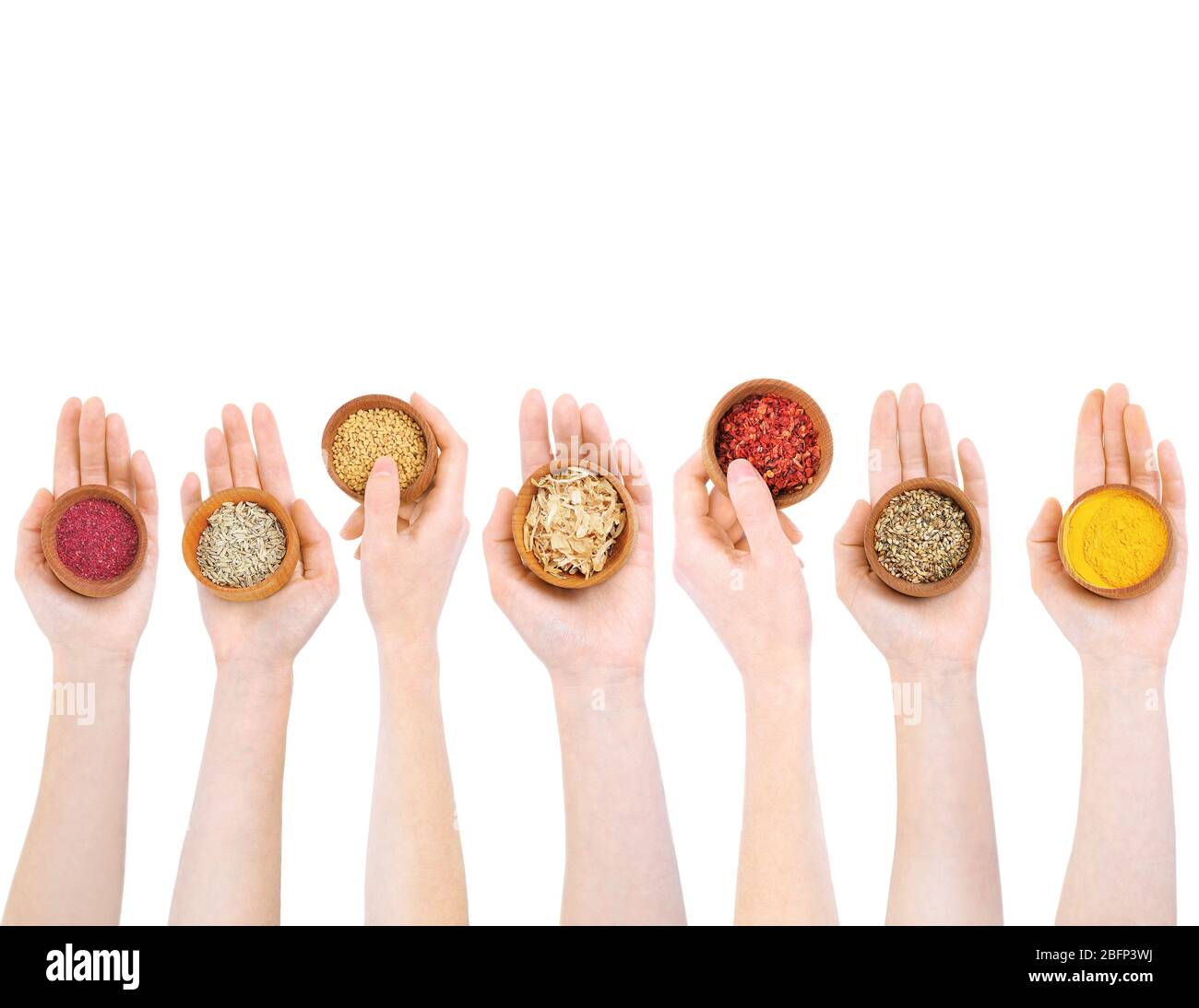 Hands holding collection of different spices in wooden bowls, isolated ...