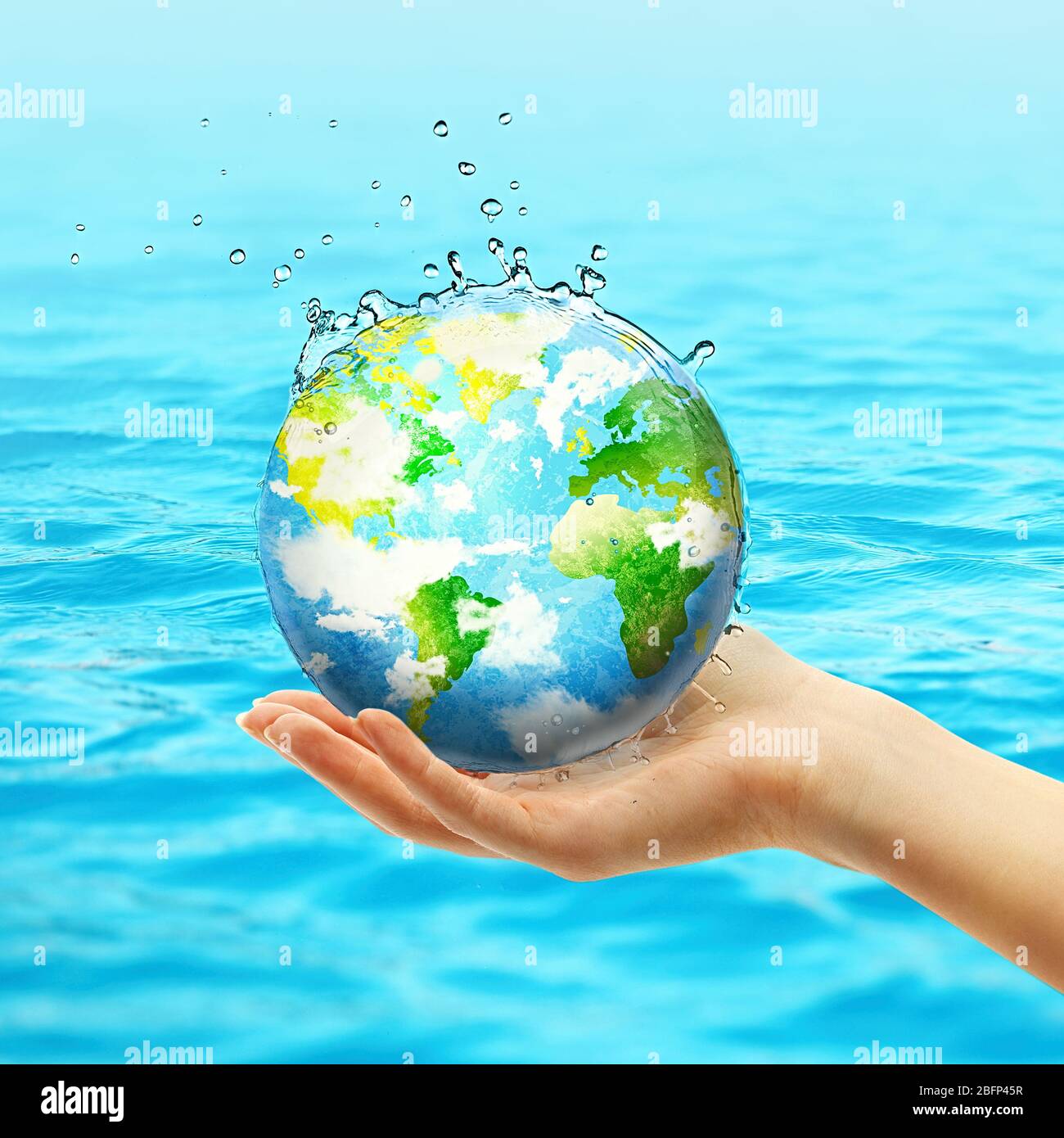 Female hand holding globe on blue water background Stock Photo - Alamy