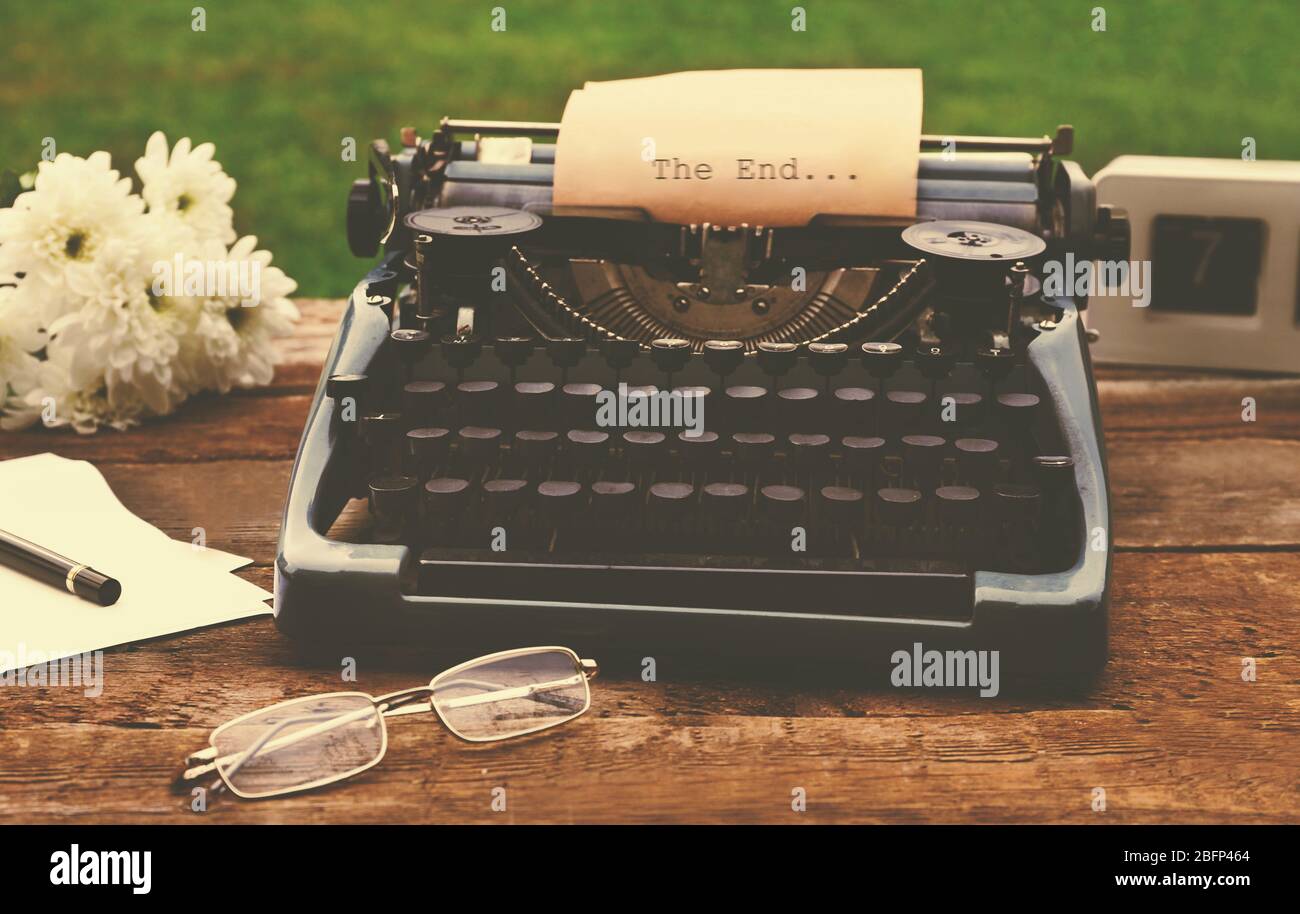 Vintage black typewriter on decorated wooden table, outdoors, close up ...