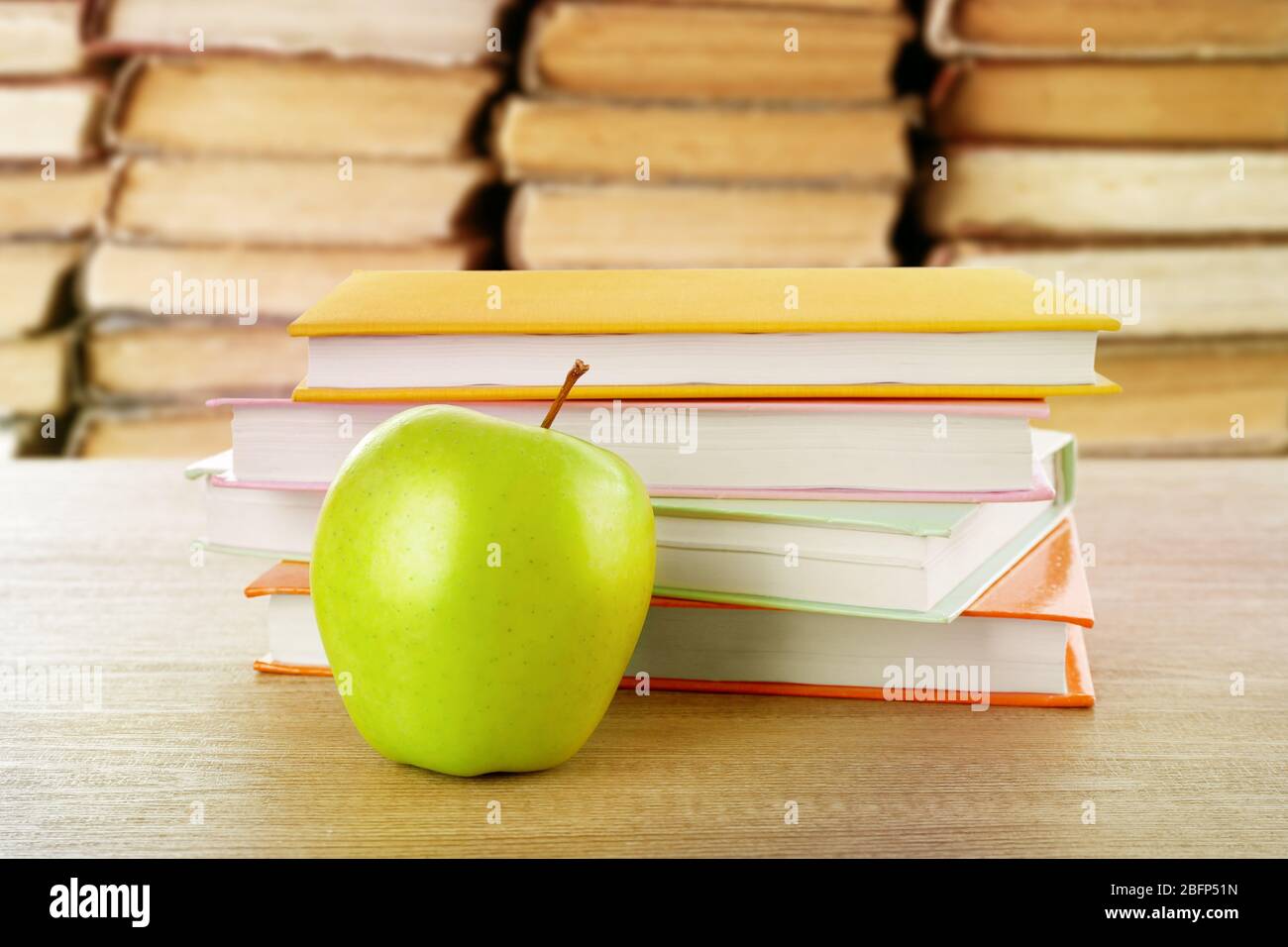 Few books with green apple on blurred library background Stock Photo ...