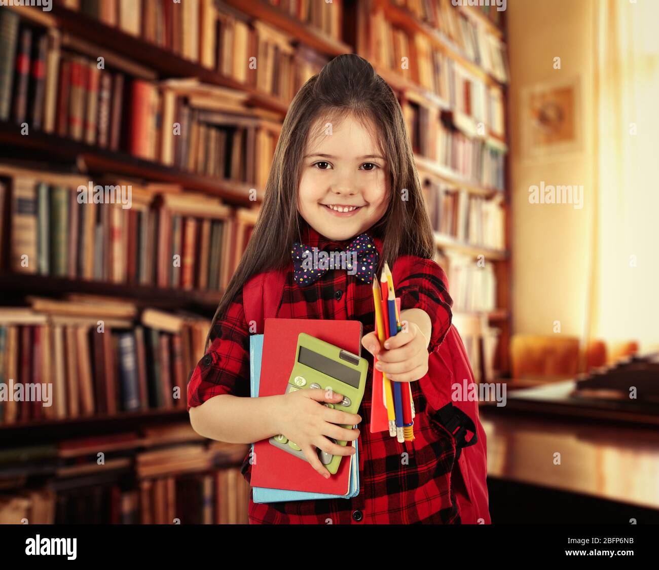 Cute little girl with backpack holding books and pencils on blurred ...