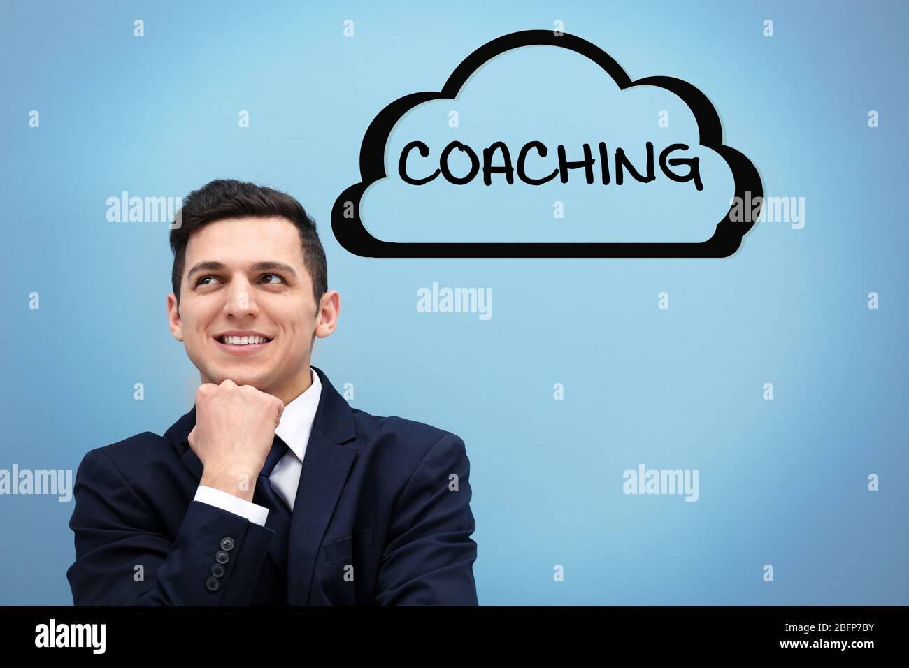 Personal coaching concept. Attractive young man in a suit against light ...