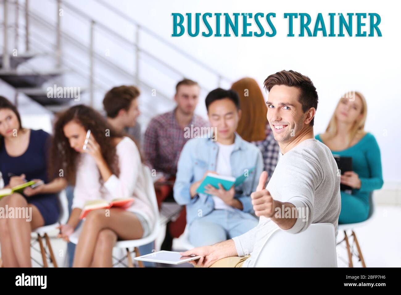 Business training concept. Happy young man sitting in front of people ...