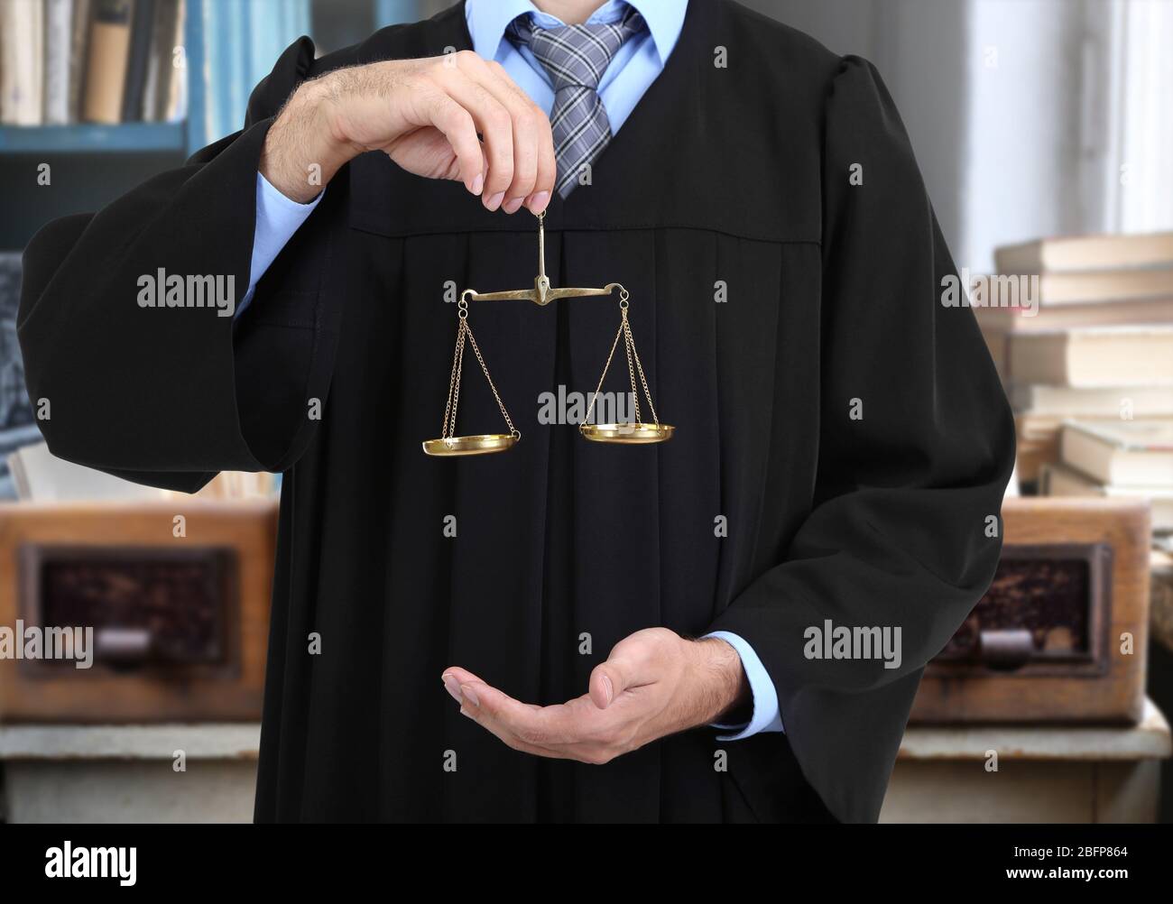 Judge holding scales of justice on blurred books background Stock Photo ...