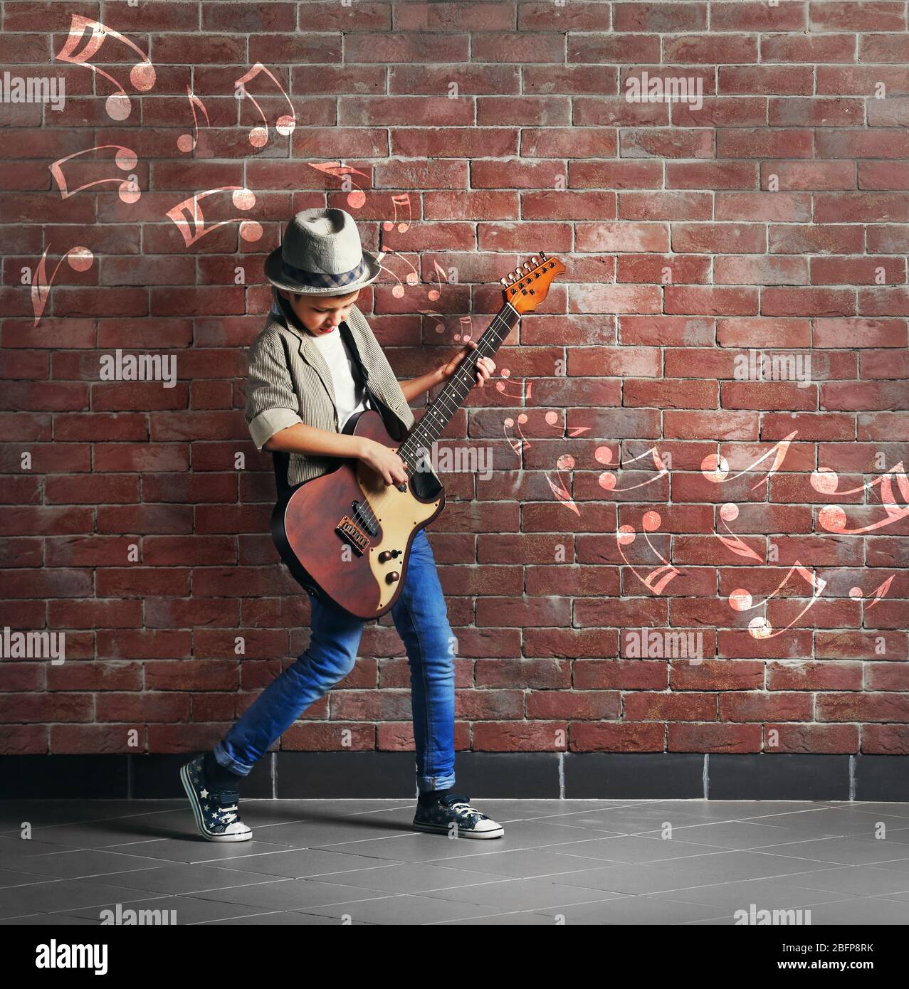 Little boy playing guitar. Musical notes design on brick wall ...