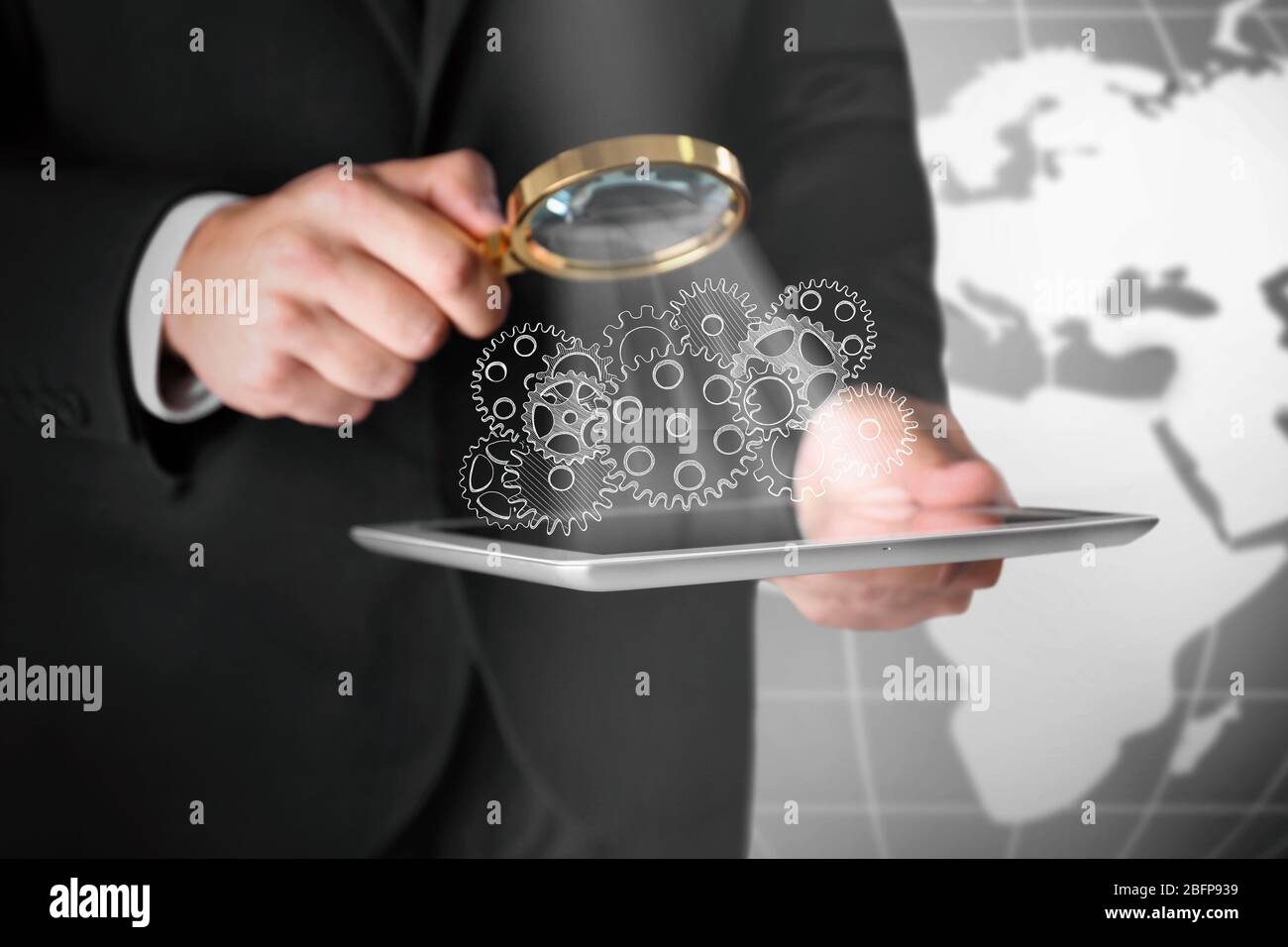 Businessman holding magnifying glass and tablet. Digital mechanism on ...