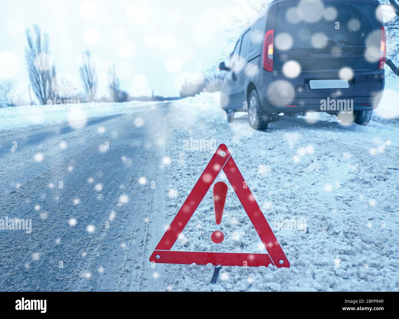Warning triangle with car breakdown on background. Winter road safety ...