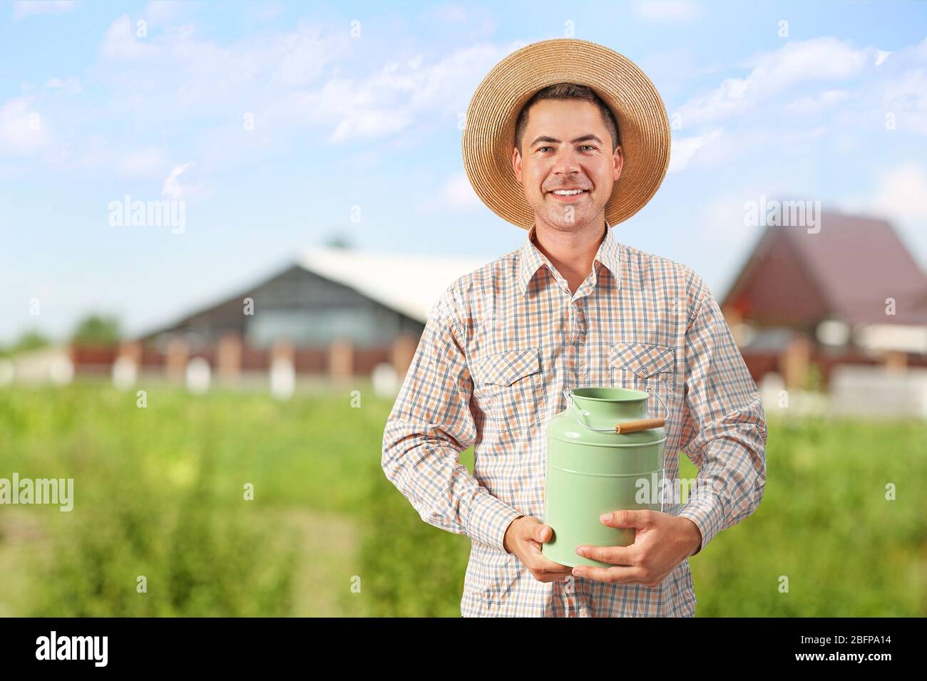 Milkman with watering can on blurred dairy farm background Stock Photo ...