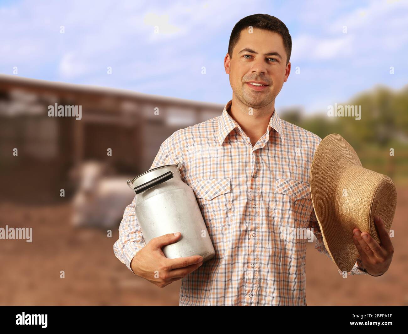 Milkman with watering can on blurred dairy farm background Stock Photo ...