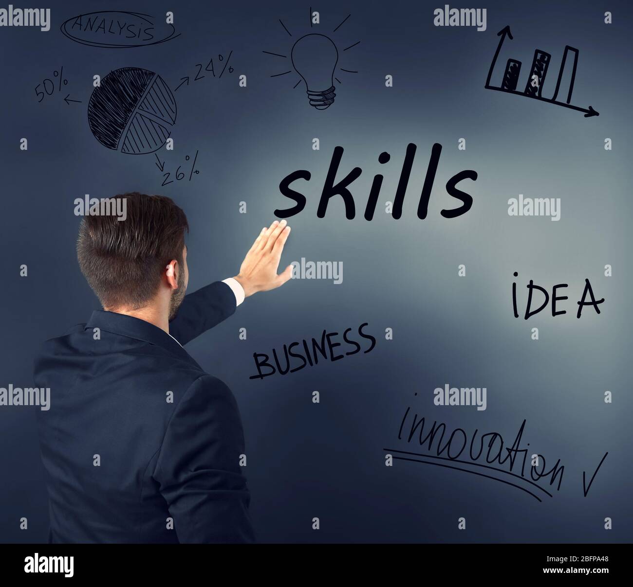 Skills. Back view of Caucasian young man in navy blue suit pointing on ...