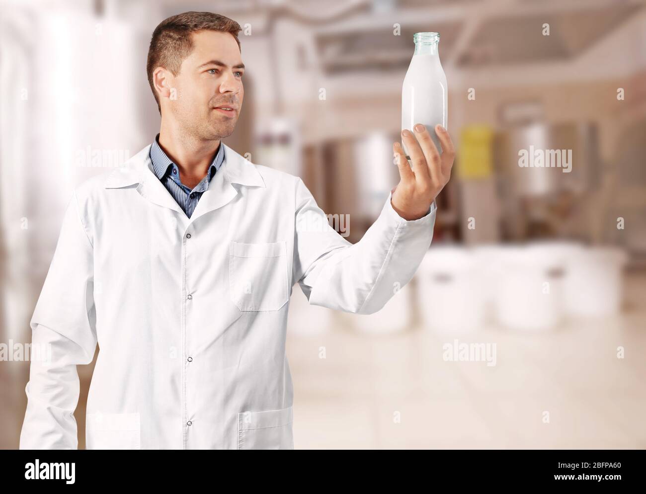 Professional expert with glass bottle of milk on blurred dairy ...