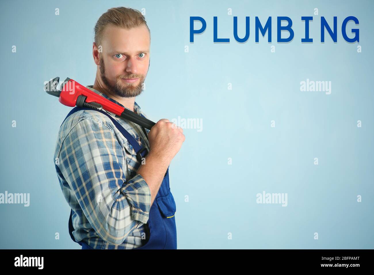 Plumbing concept. Portrait of handsome plumber with pipe wrench on ...