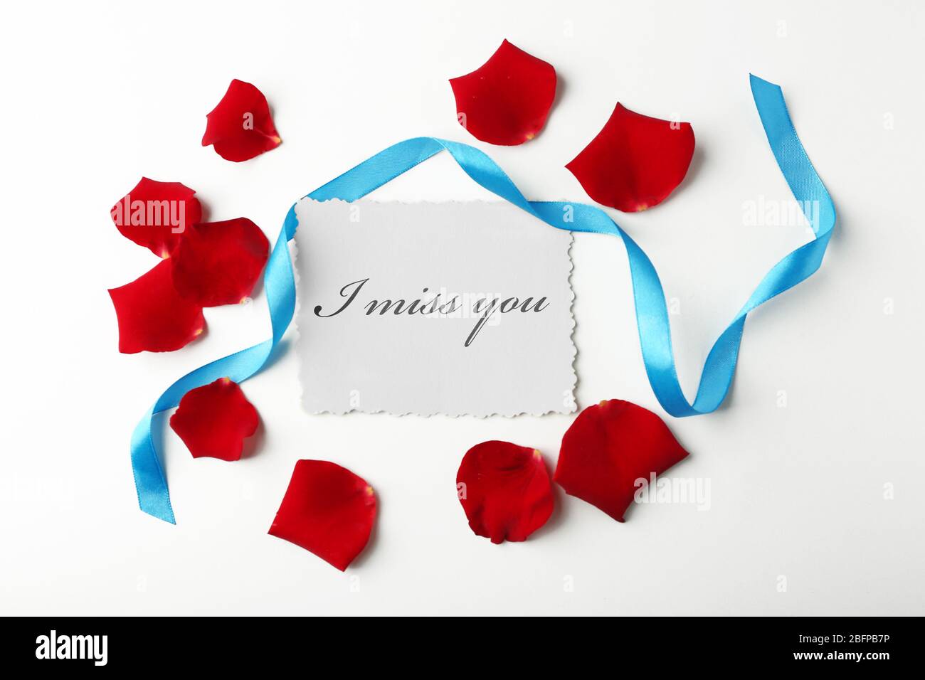 Rose petals, ribbon and card on white background Stock Photo - Alamy