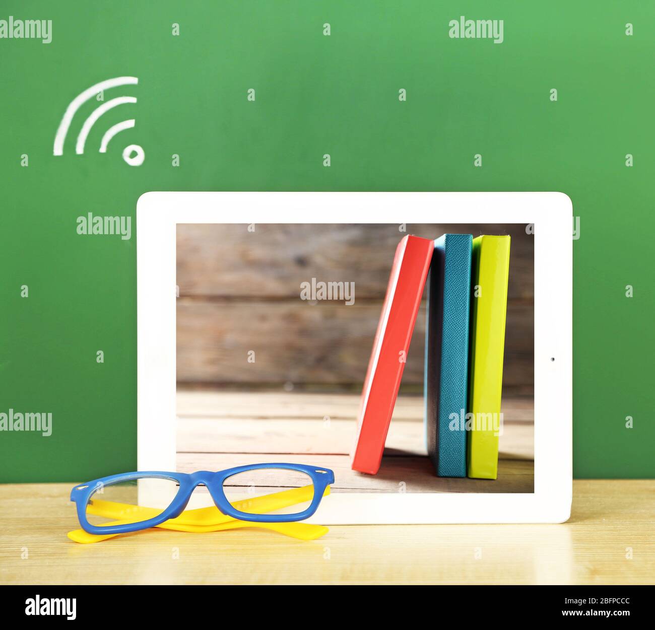 Tablet with stationery wallpaper on screen. WI-FI sign on chalkboard ...