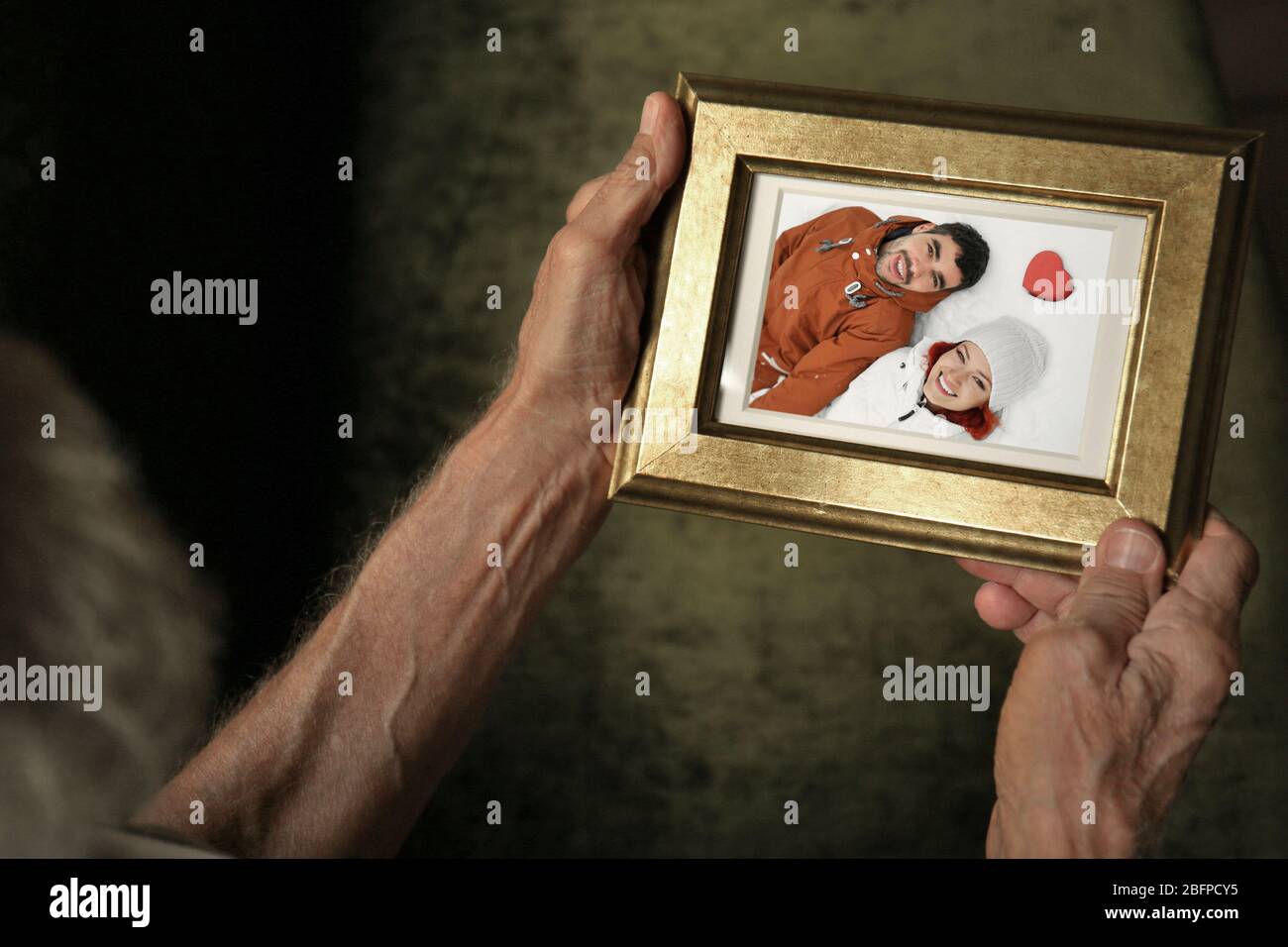 Elderly man holding photo frame with picture of young couple. Happy ...